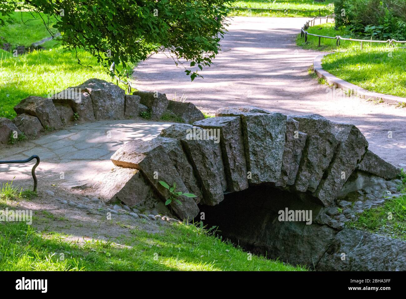 Humpback stone pedestrian bridge connecting two alleys in the city Park ...