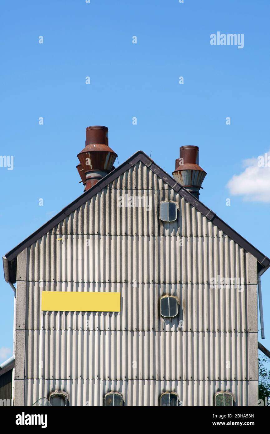 The sheet metal facade of a metalworking workshop with rusted chimneys ...