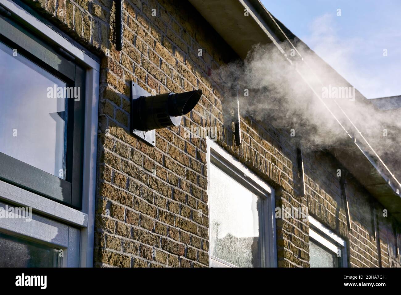Modern black plastic chimney on brick wall of a house with smoke in ...