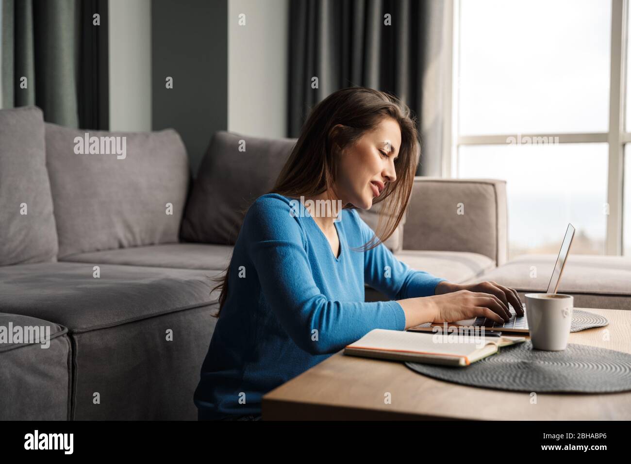Image of charming young happy woman using laptop and smiling while ...