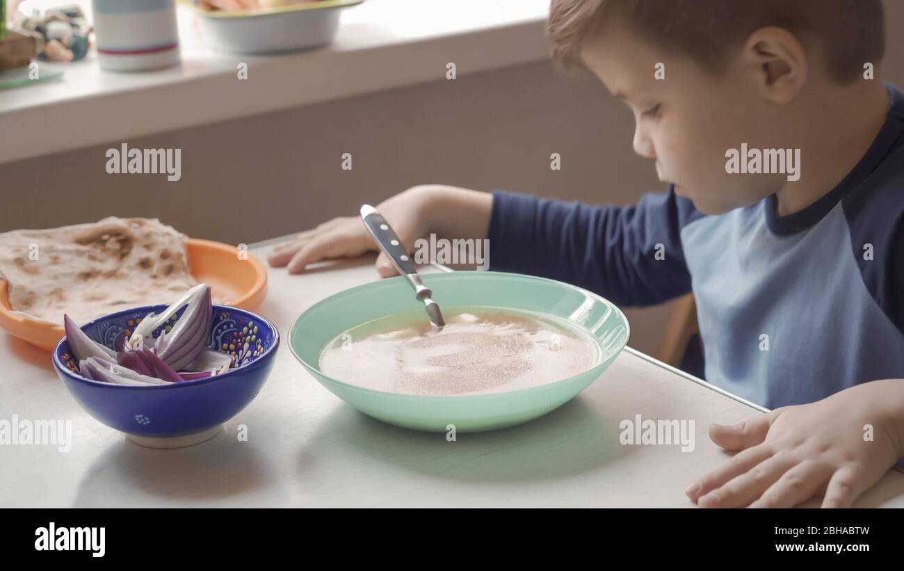 Young Boy Eats Soup Sitting At Dining Room Table Stock Photo - Alamy