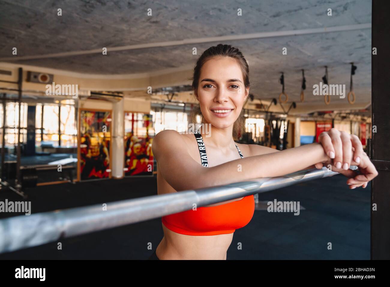 Attractive smiling young fit sportswoman standing in the gym, resting ...