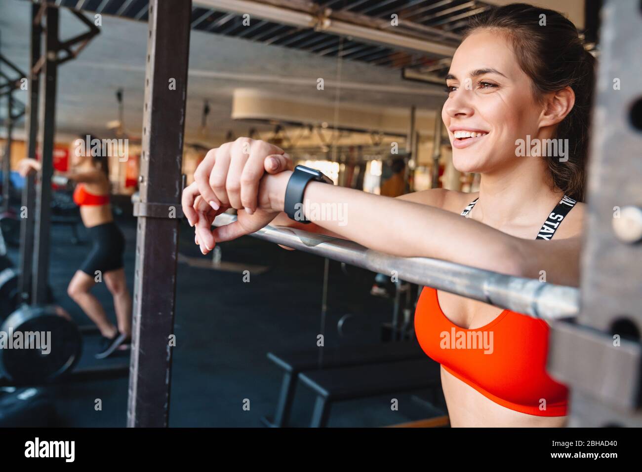 Attractive smiling young fit sportswoman standing in the gym, resting ...