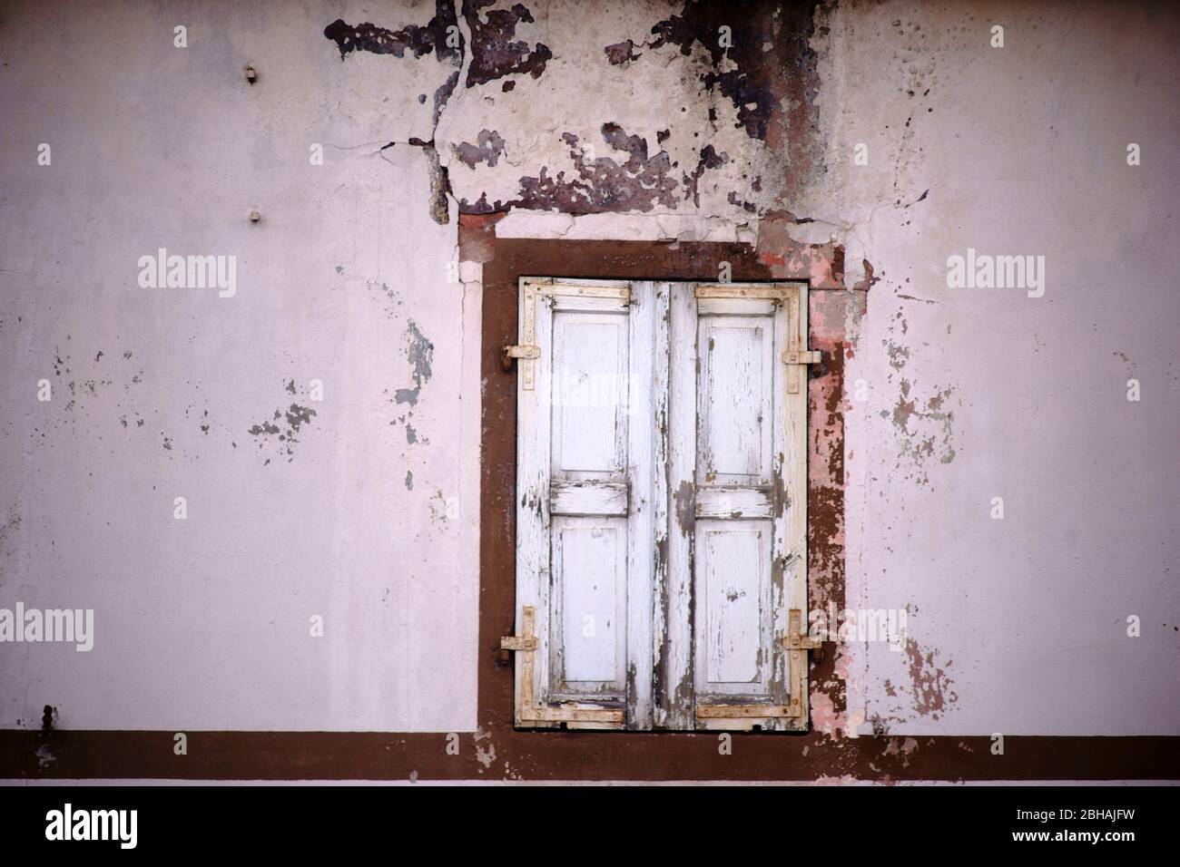 Closed and ailing wooden shutters of an old and dilapidated residential ...