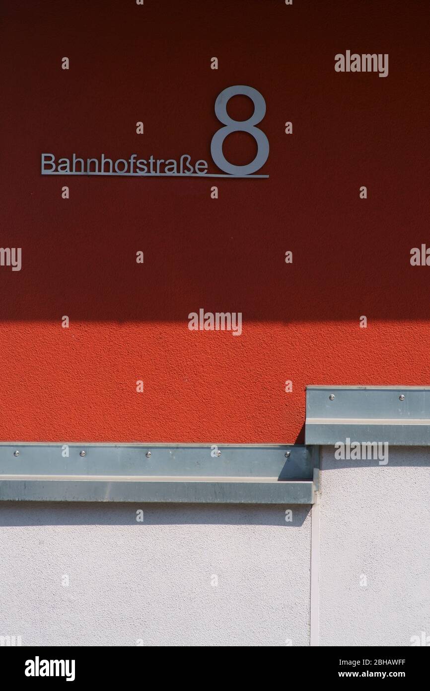 The detail of a modern house wall with a house number and a street sign ...