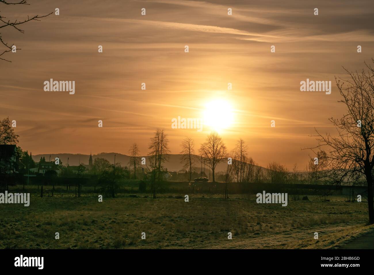 Sunrise on a field with trees and houses Stock Photo - Alamy