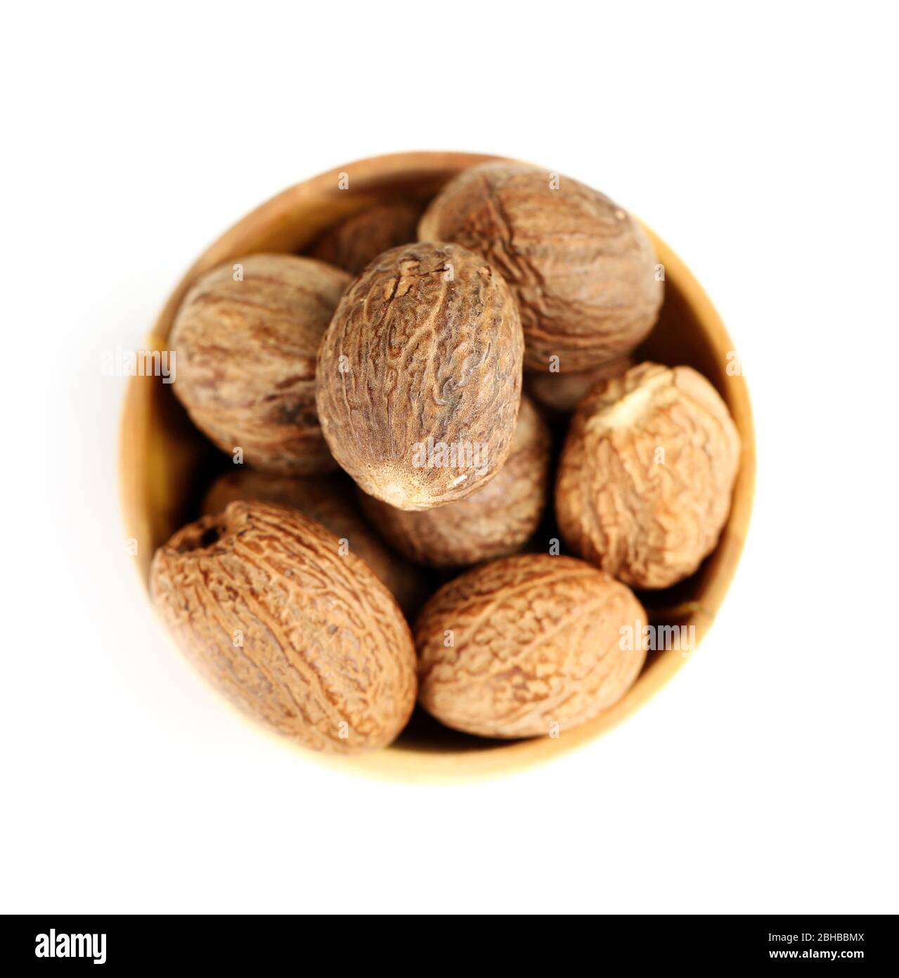 Nutmeg in wooden bowl, isolated on white Stock Photo - Alamy