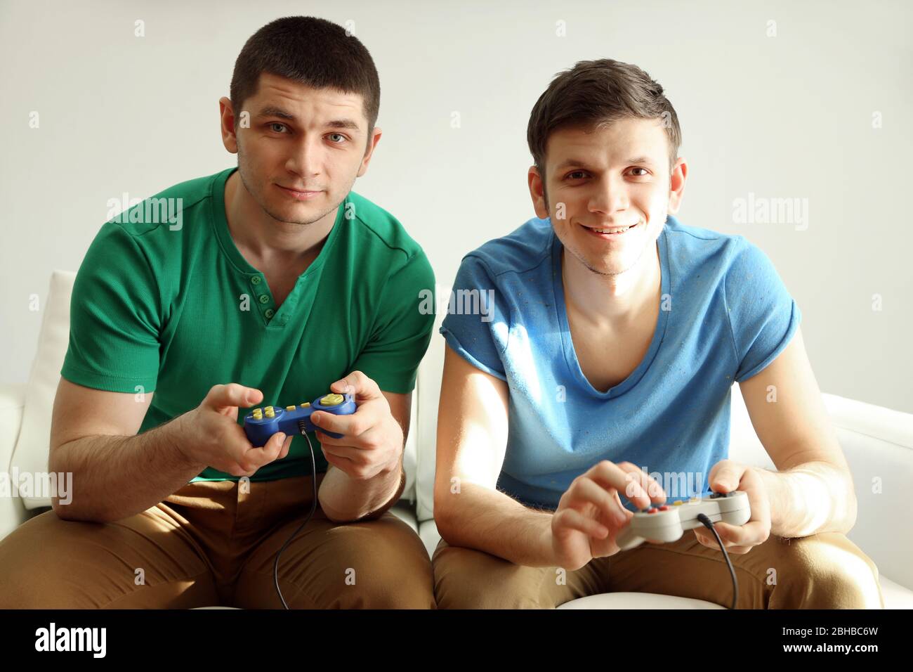 Two handsome young men playing video games in room Stock Photo - Alamy