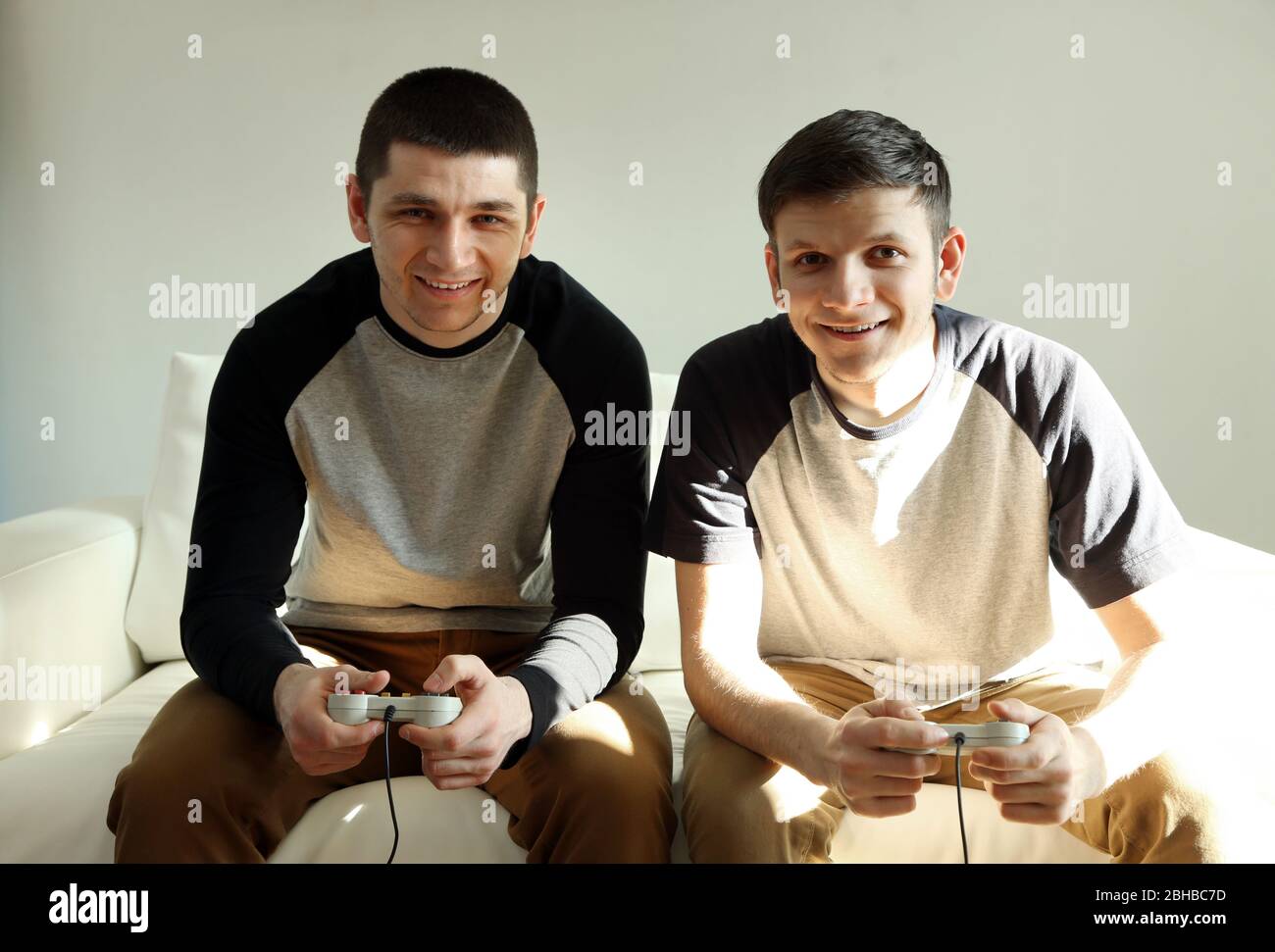 Two handsome young men playing video games in room Stock Photo - Alamy