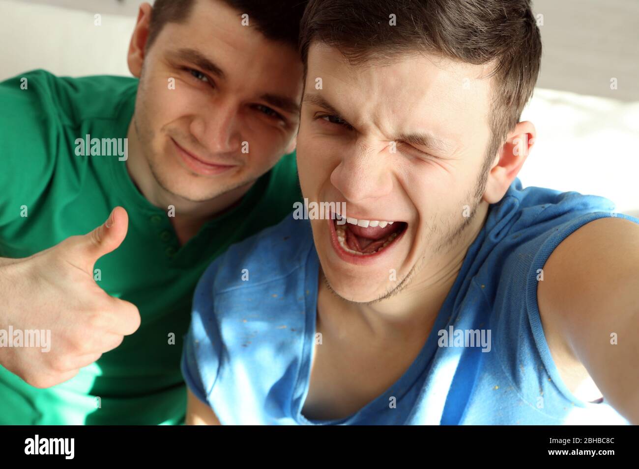 Two handsome young men sitting on sofa and making photo on mobile phone ... Two handsome young men sitting on sofa and making photo on mobile phone ...