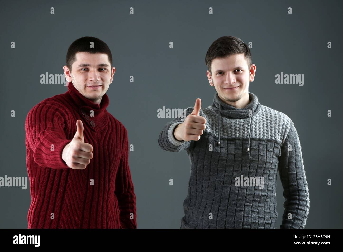 Two handsome young men on gray background Stock Photo - Alamy