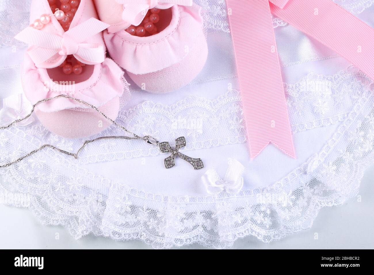 Baby shoe and cross for Christening Stock Photo - Alamy