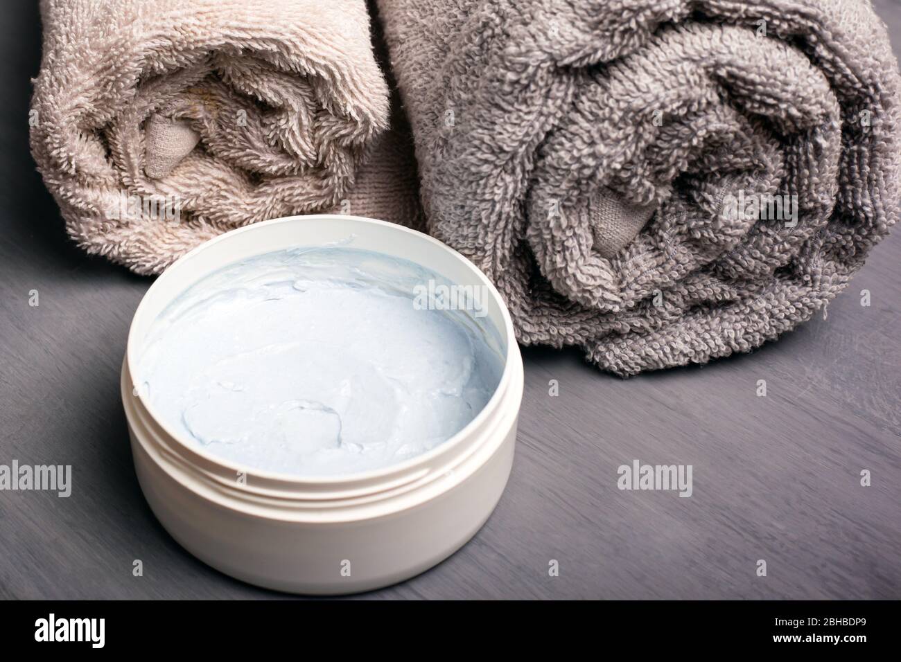 pastel-colored rolled towels and body scrub on a gray background close ...