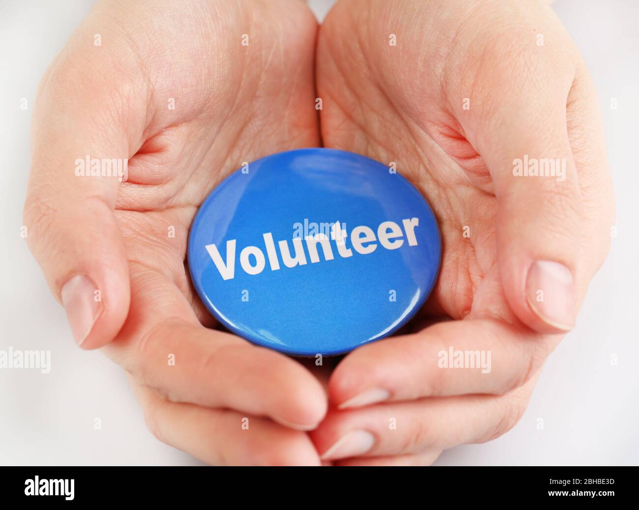 Round volunteer button in hands isolated on white Stock Photo - Alamy