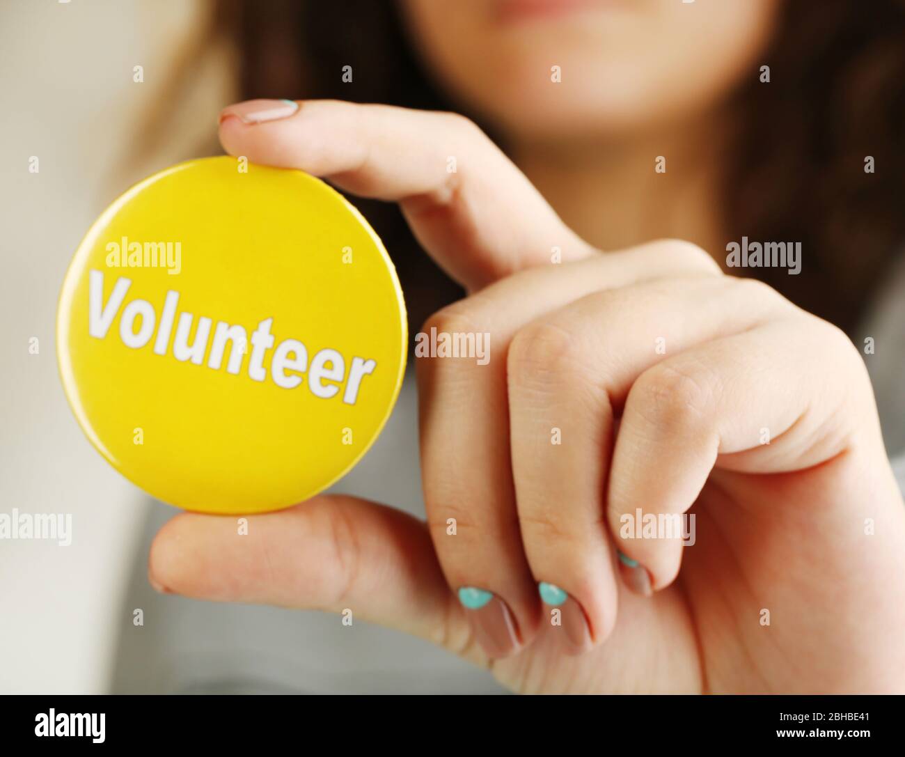 Round volunteer button in hand close-up Stock Photo - Alamy