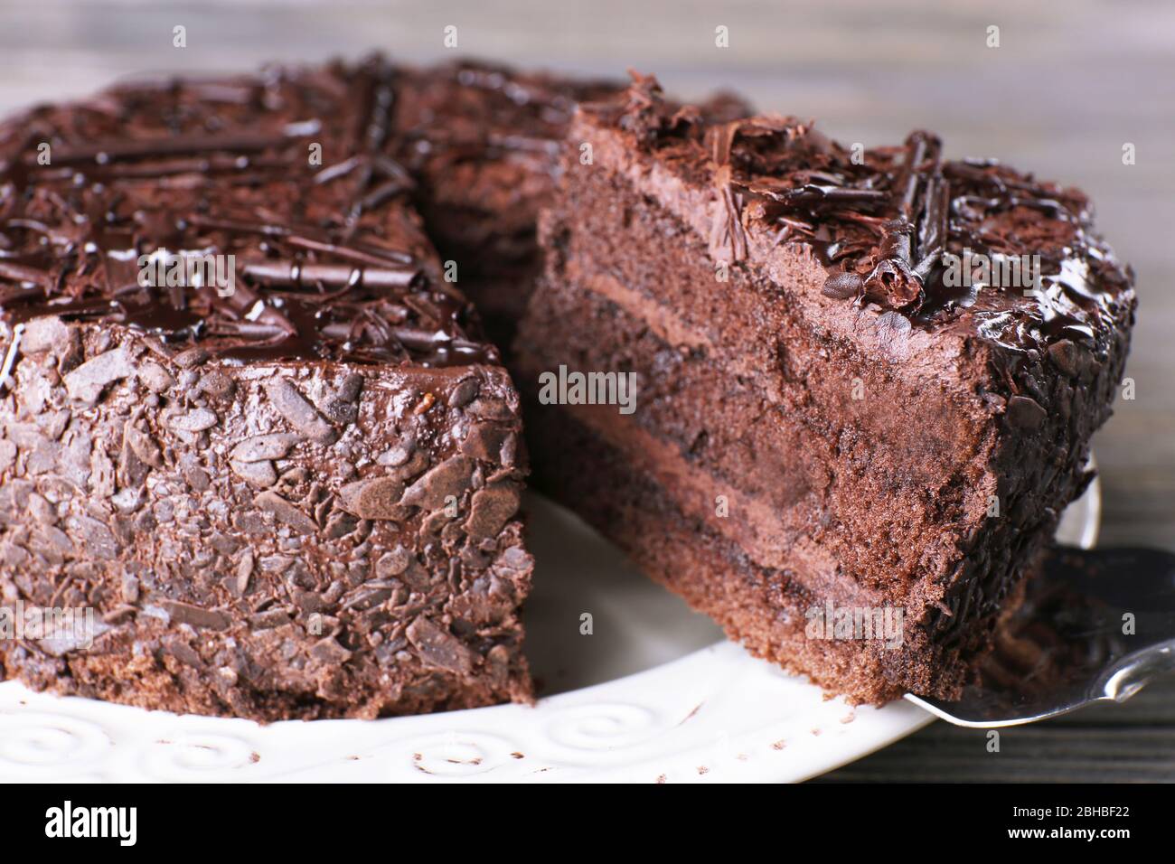 Sliced tasty chocolate cake in plate with blade on wooden table ...