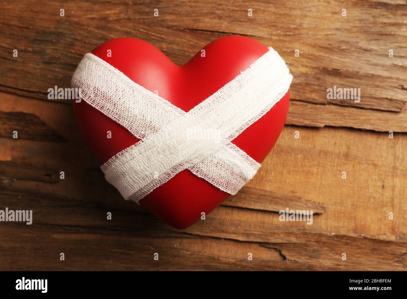 Tied heart with bandage on rustic wooden table background Stock Photo ...
