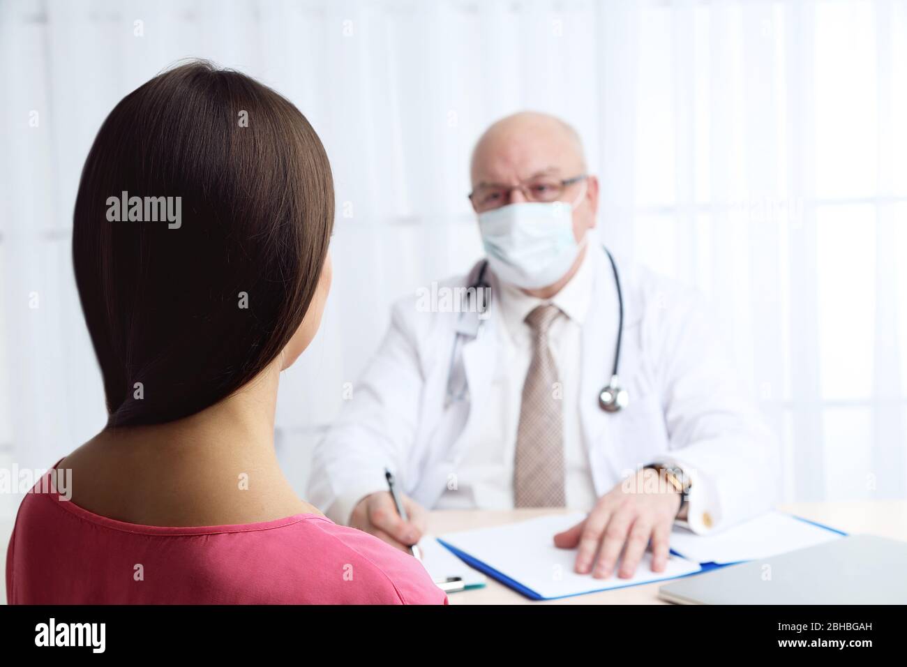 Professional doctor receiving patient in his office on white curtain ...