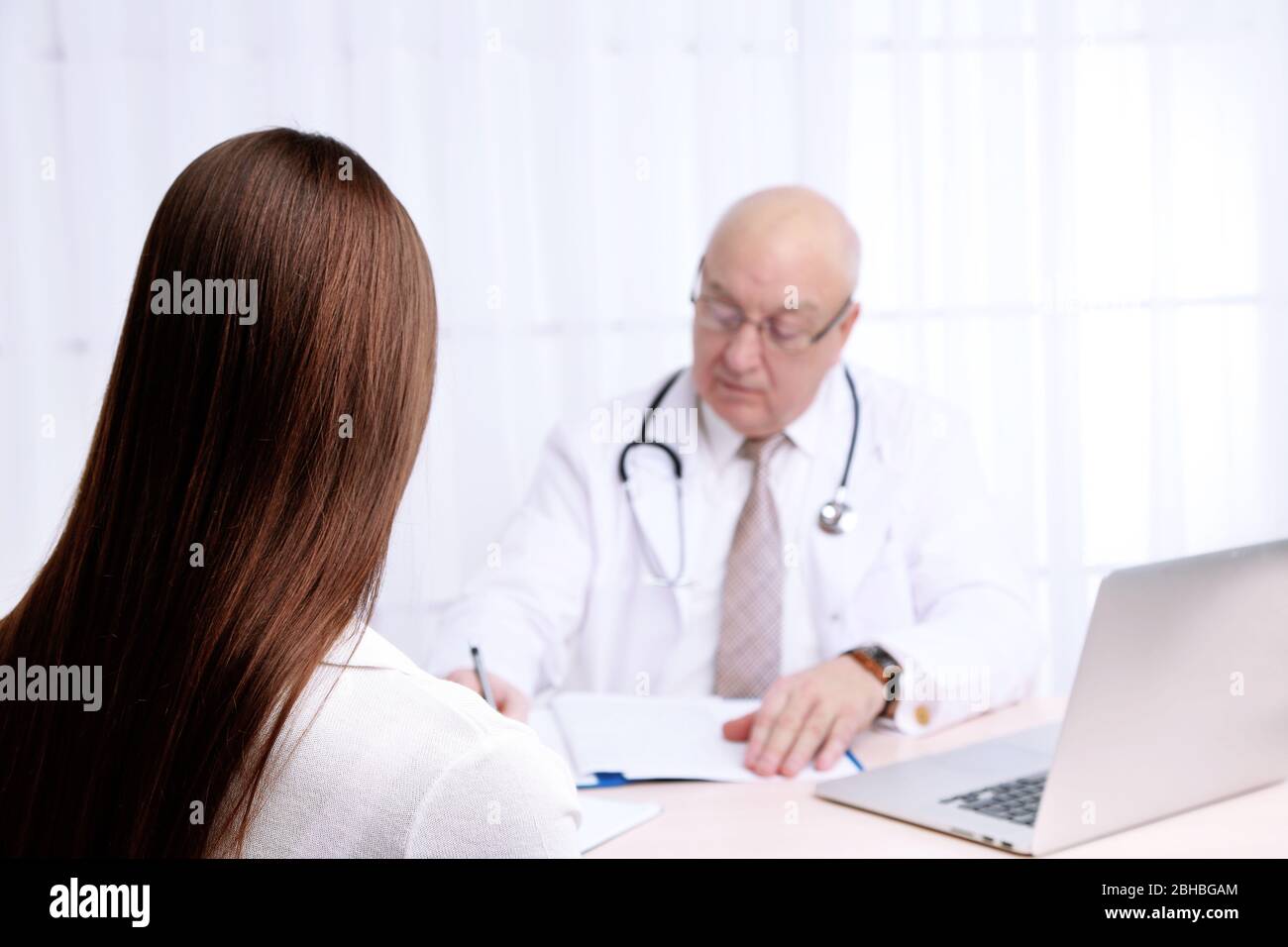 Professional doctor receiving patient in his office on white curtain ...
