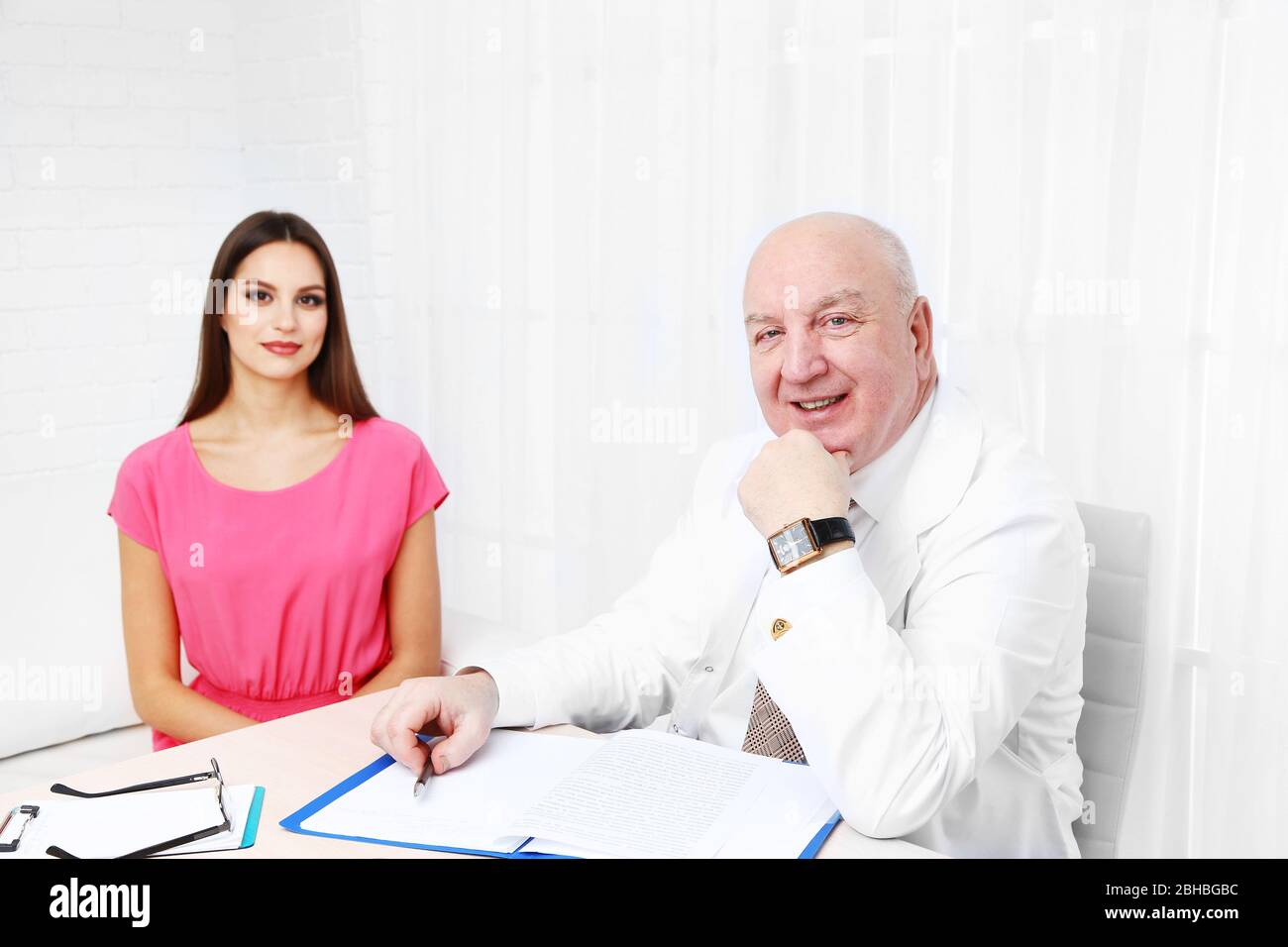 Professional doctor receiving patient in his office on white curtain ...