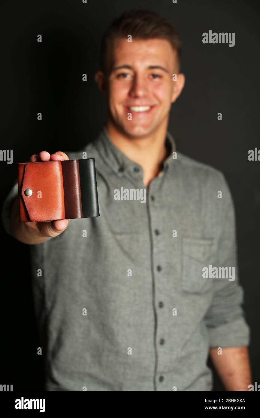 Man holding hand made leather wallets on black background Stock Photo ...
