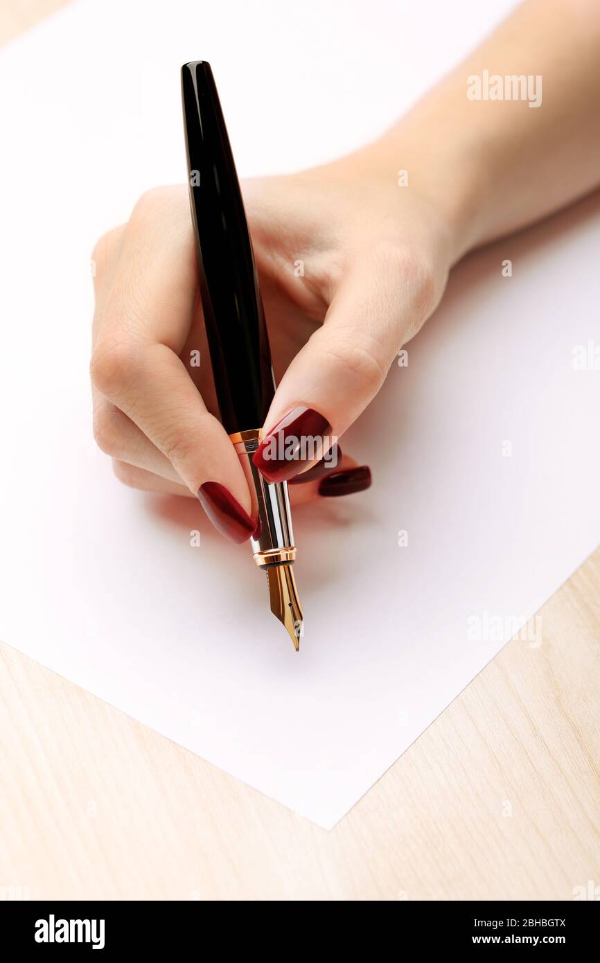 Female hand writing letter on white sheet of paper by fountain pen on ...