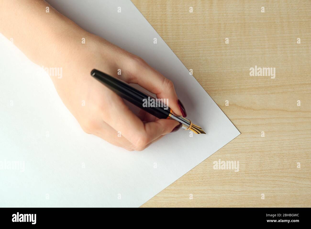 Female hand writing letter on white sheet of paper by fountain pen on ...
