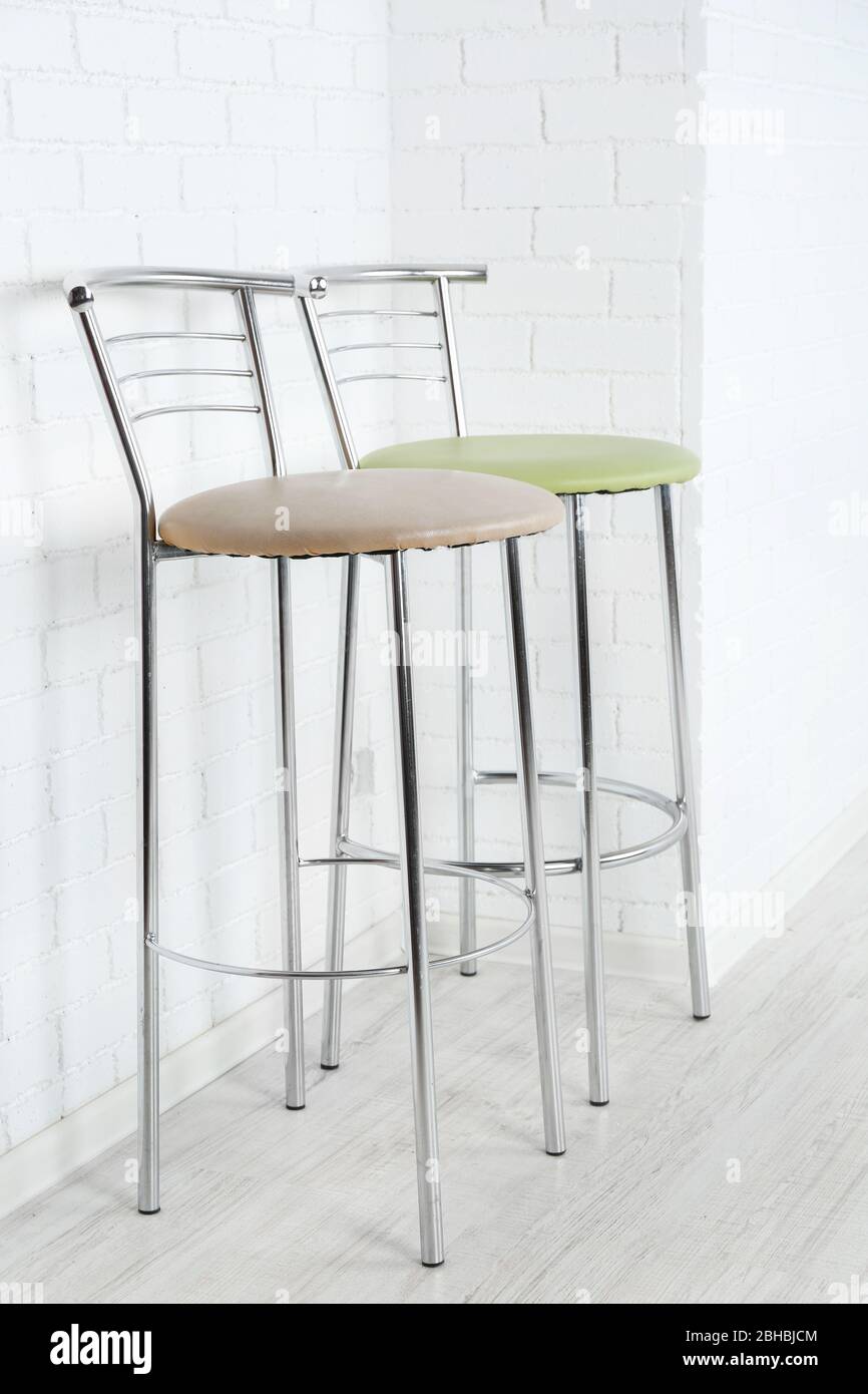 Bar high chairs on white brick wall background Stock Photo - Alamy