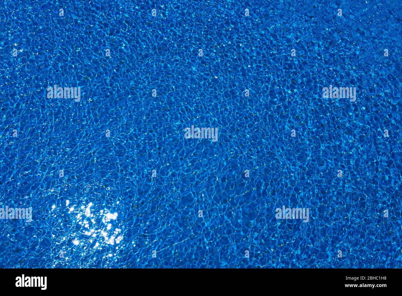 Swimming pool, blue clear water in the outdoor pool, with sun flare on ...
