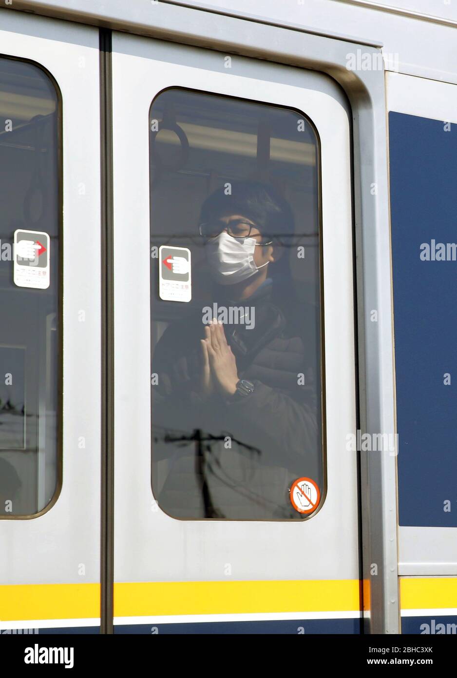 Amagasaki, Japan. 24th Apr 2020. A passenger prays as his train passes ...