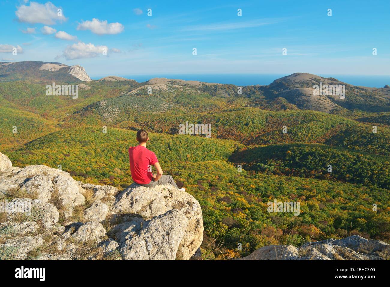 Man sitting on the edge of cliff mountain. Conceptual scene Stock Photo ...