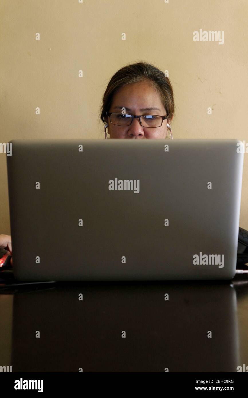 Photo of a Filipino woman working on a laptop computer at home Stock ...