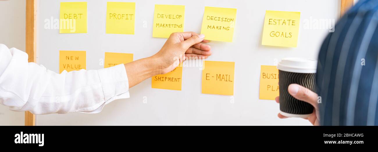Business people arranging sticky notes commenting and brainstorming on ...