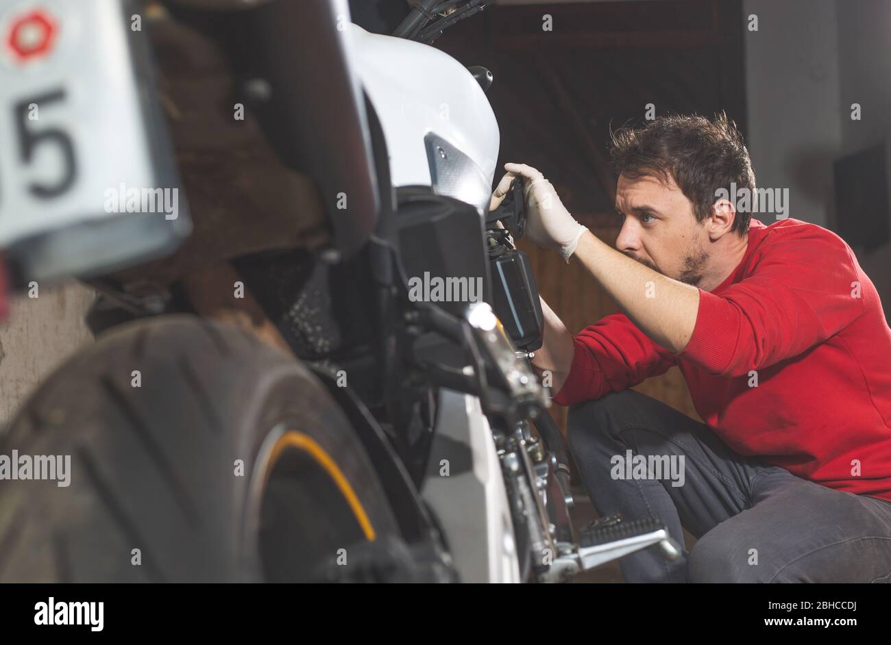 Man repairing, doing maintenance of his motorcycle, motorbike in the ...