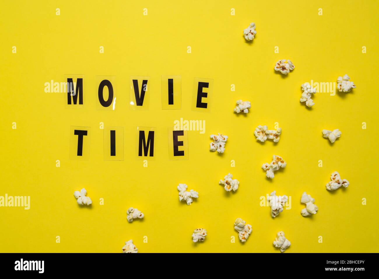 Movie Time text lettering with scattered salty popcorn on yellow ...