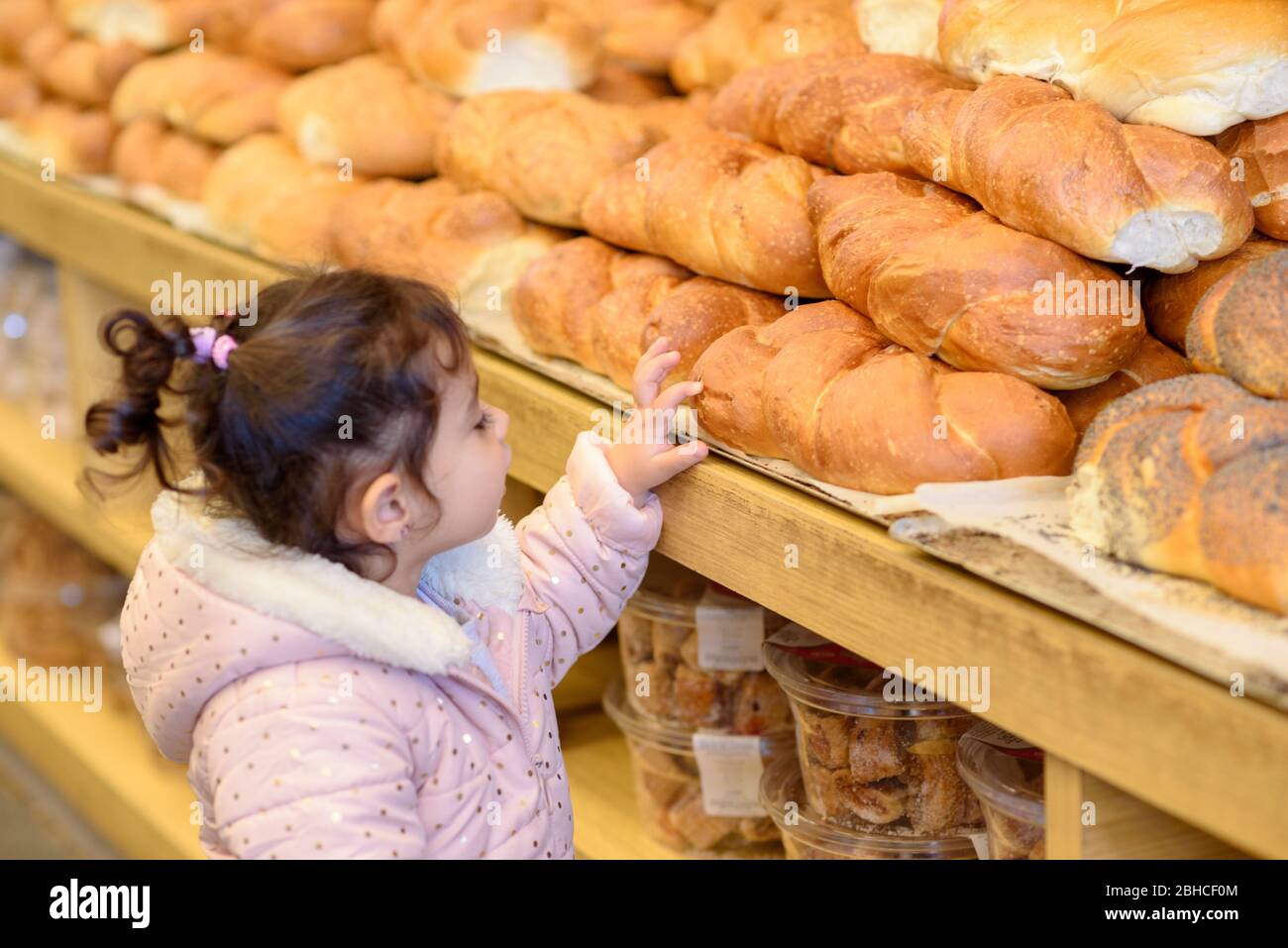 Cute toddler girl in bakery store choosing fresh bread loaf Stock Photo ...