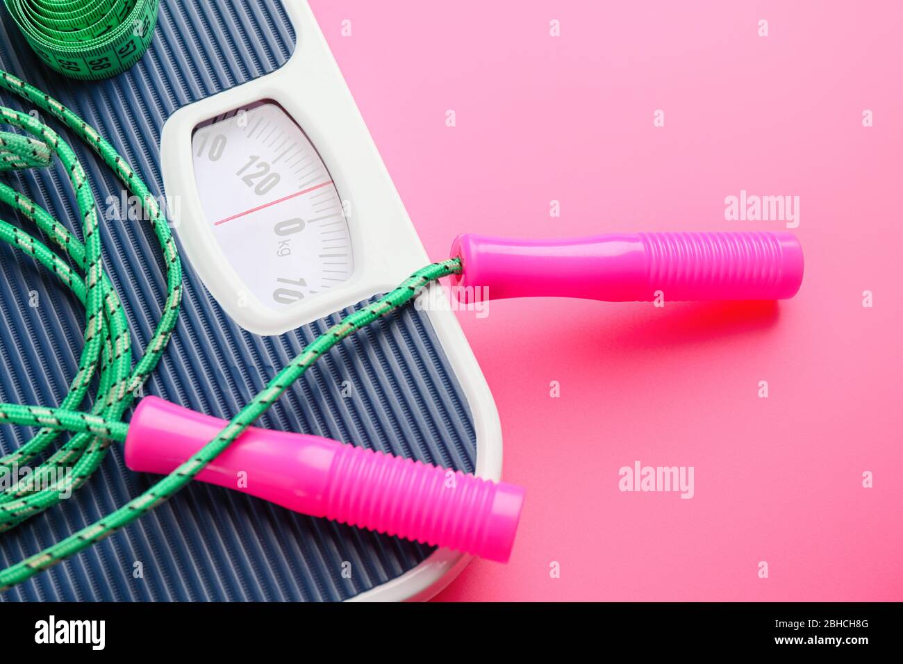Weight scales with jumping rope on color background, closeup. Slimming ...