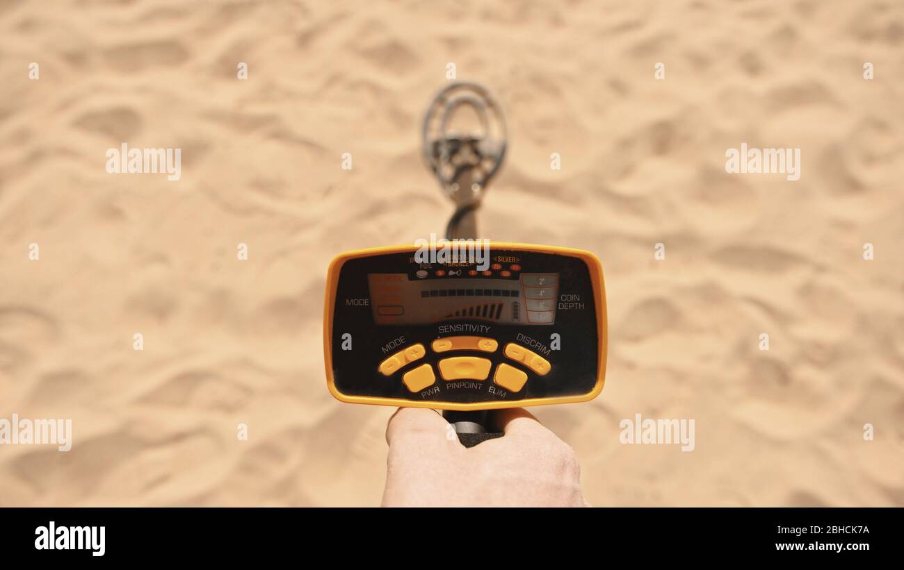 Person scanning sand with metal detector on the beach. Point of view ...