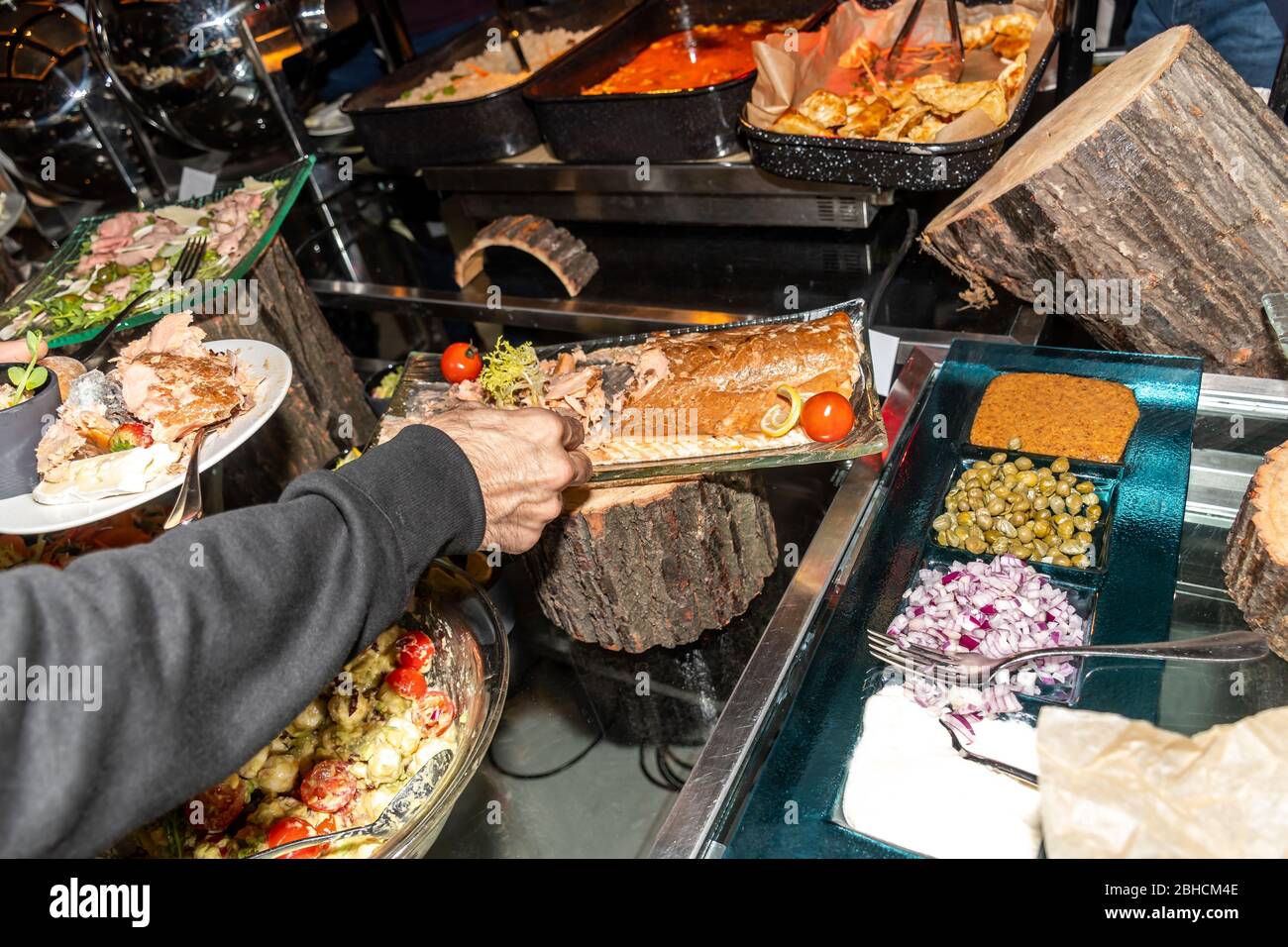 People around table during brunch buffet with hands, putting foods on ...