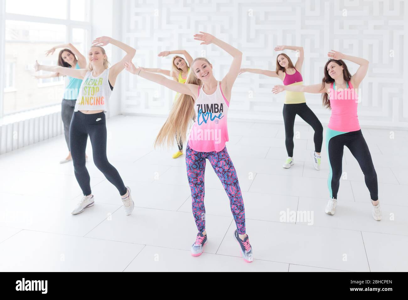 Group of young women dancing with hands raised up at Zumba dance ...