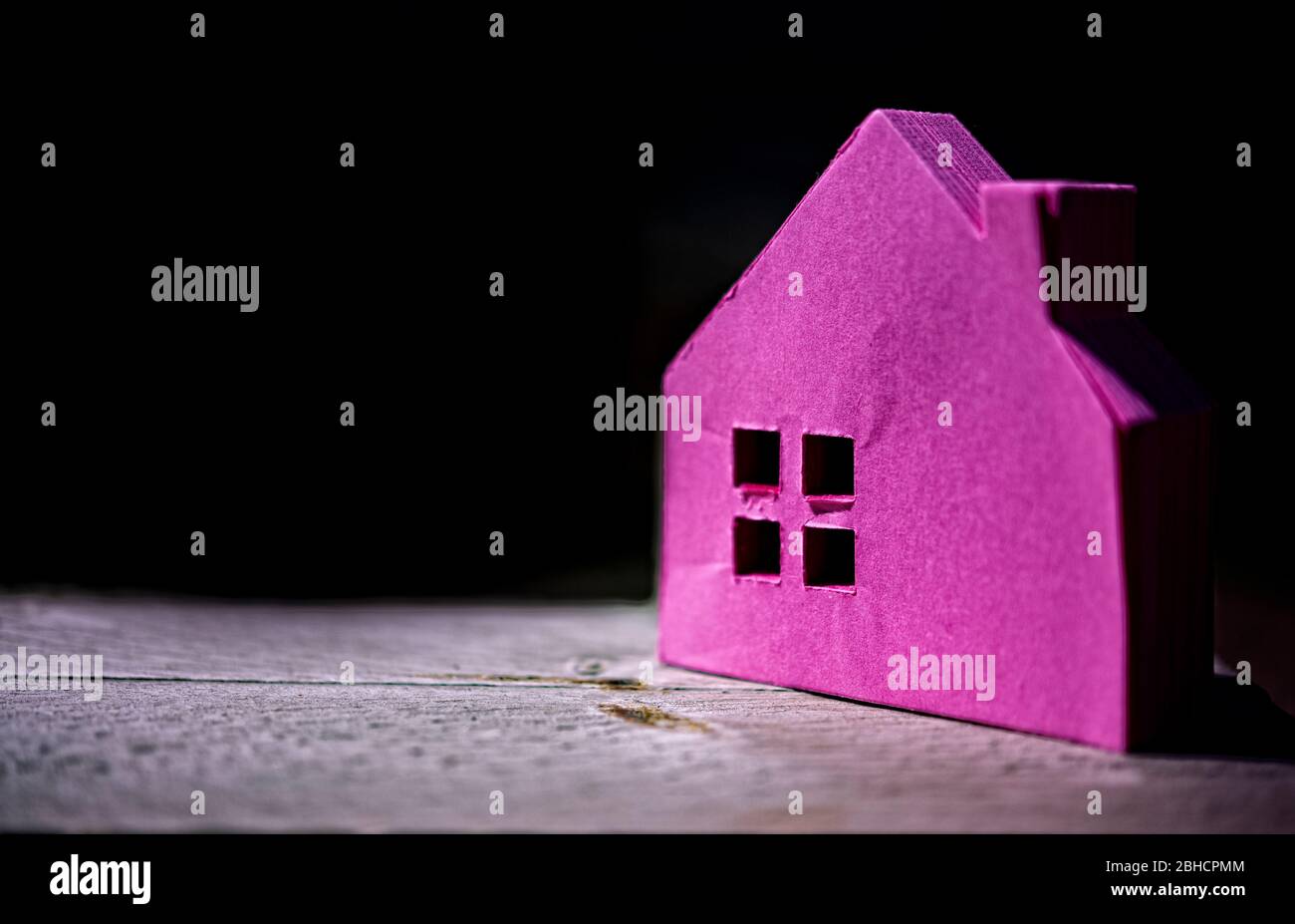 A pink post it note house side lit by sunlight . Housing market concept ...