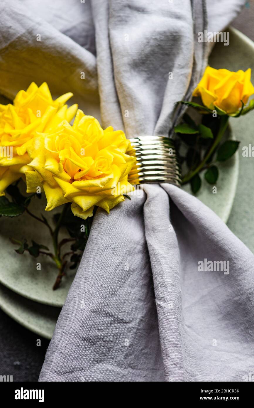 Table setting with yellow roses and cutlery on rustic table with copy ...