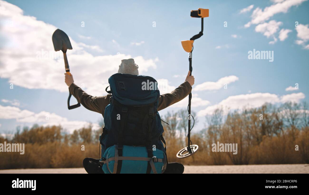 Woman with the shovel and backpack searching sand with the metal ...