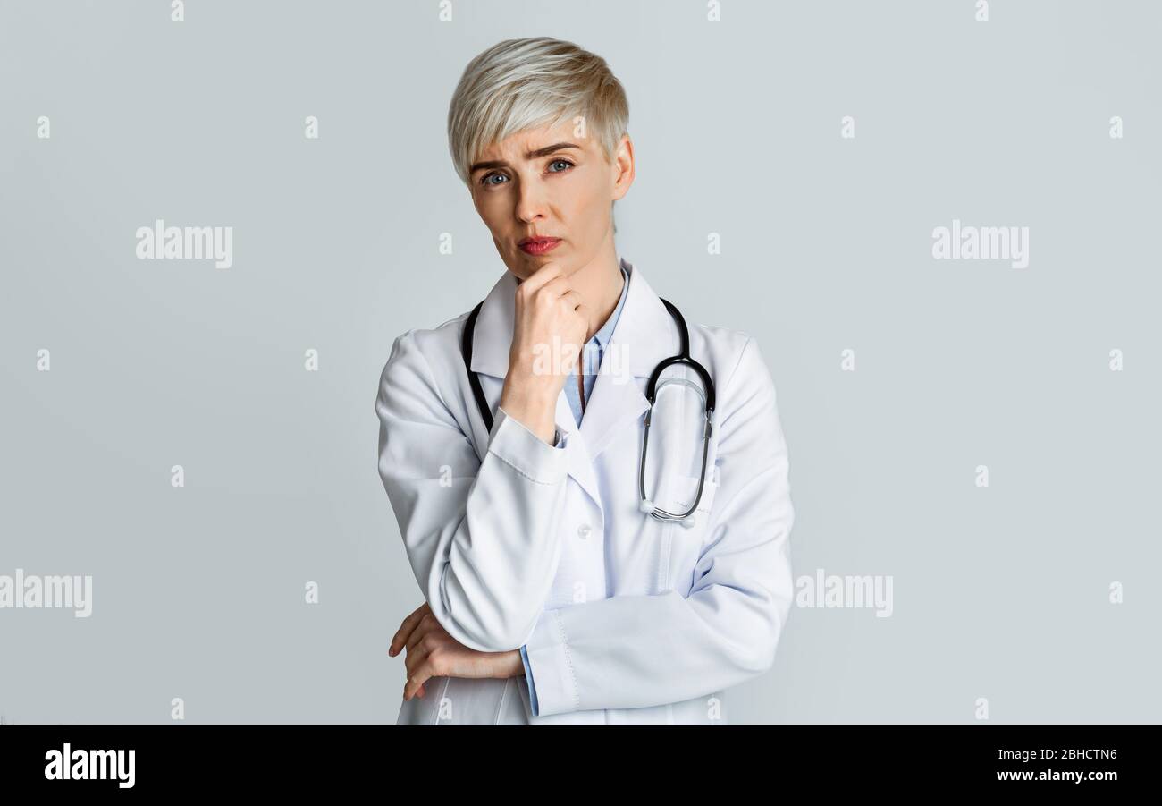 Serious woman doctor puts her hand to chin Stock Photo - Alamy