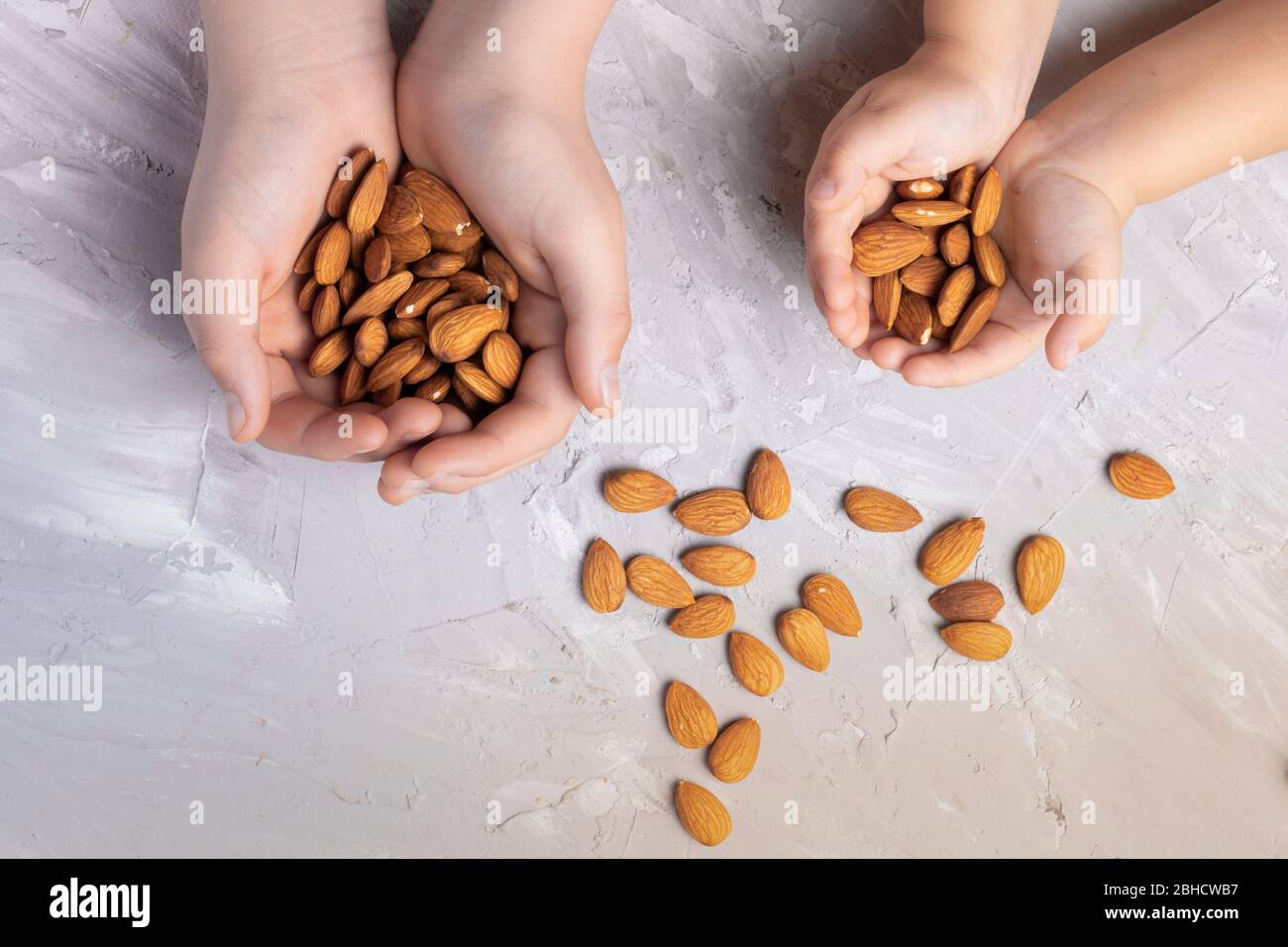 Organic Almonds in kids hands on grey table, Fla tlay Stock Photo - Alamy