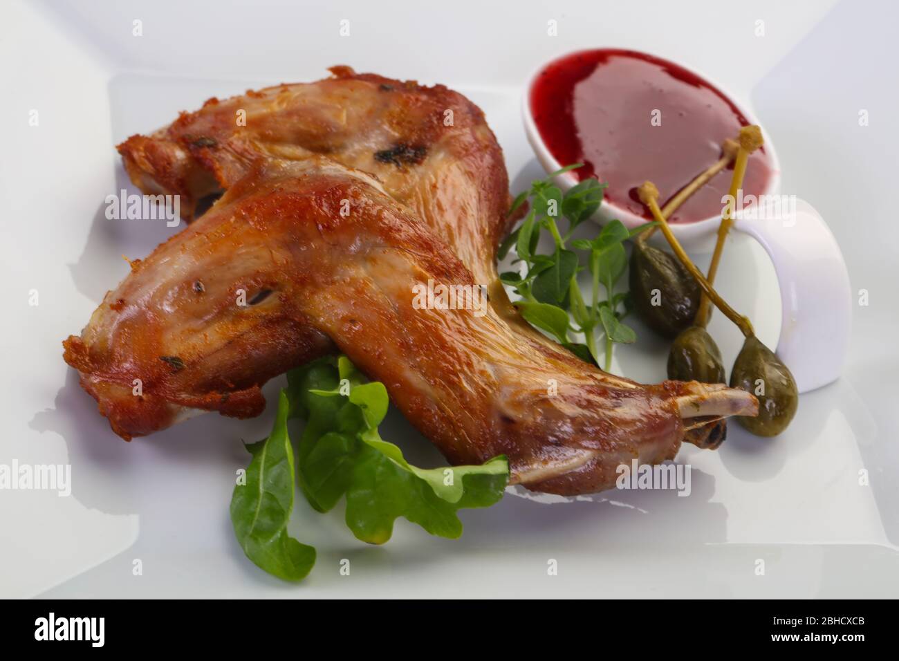Roasted rabbit legs with cowberry sauce Stock Photo - Alamy