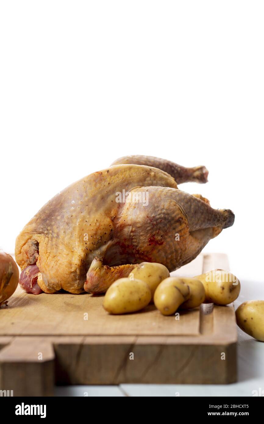 Uncooked whole chicken ready for cooking with vegetables on a chopping ...