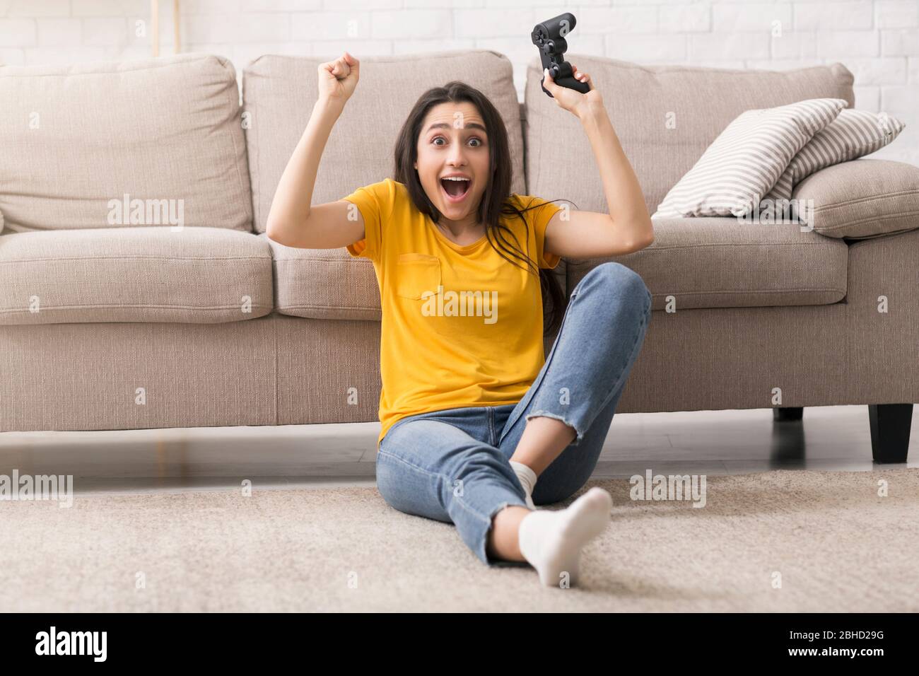 Self isolation hobbies. Young girl with joystick feeling happy for ...