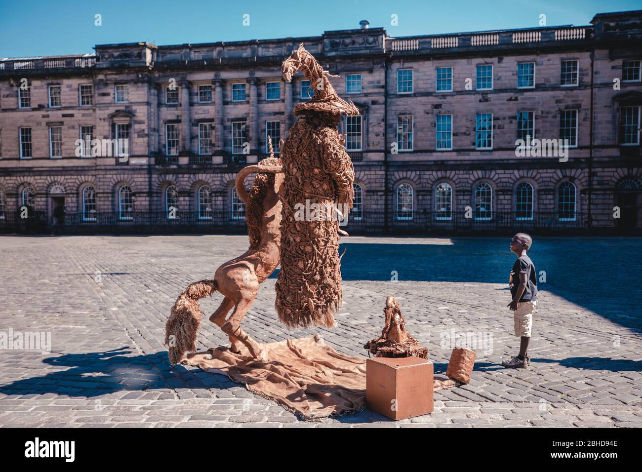 A boy standing in front of a human statue amazed by the magic. High ...