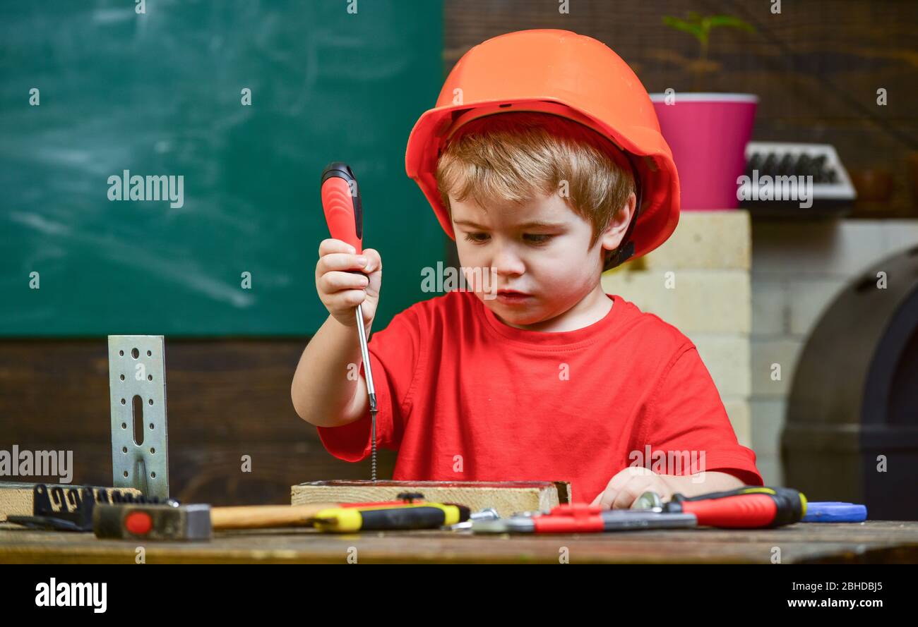 Kid boy in orange hard hat or helmet, study room background. Little ...
